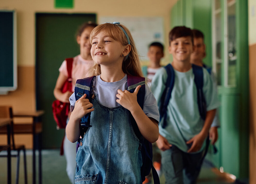 Happy girl and her classmates entering the classroom on first day of ...